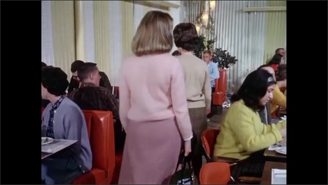 1960s: Teenagers sit at table in classroom and hold meeting. Girls walk ...